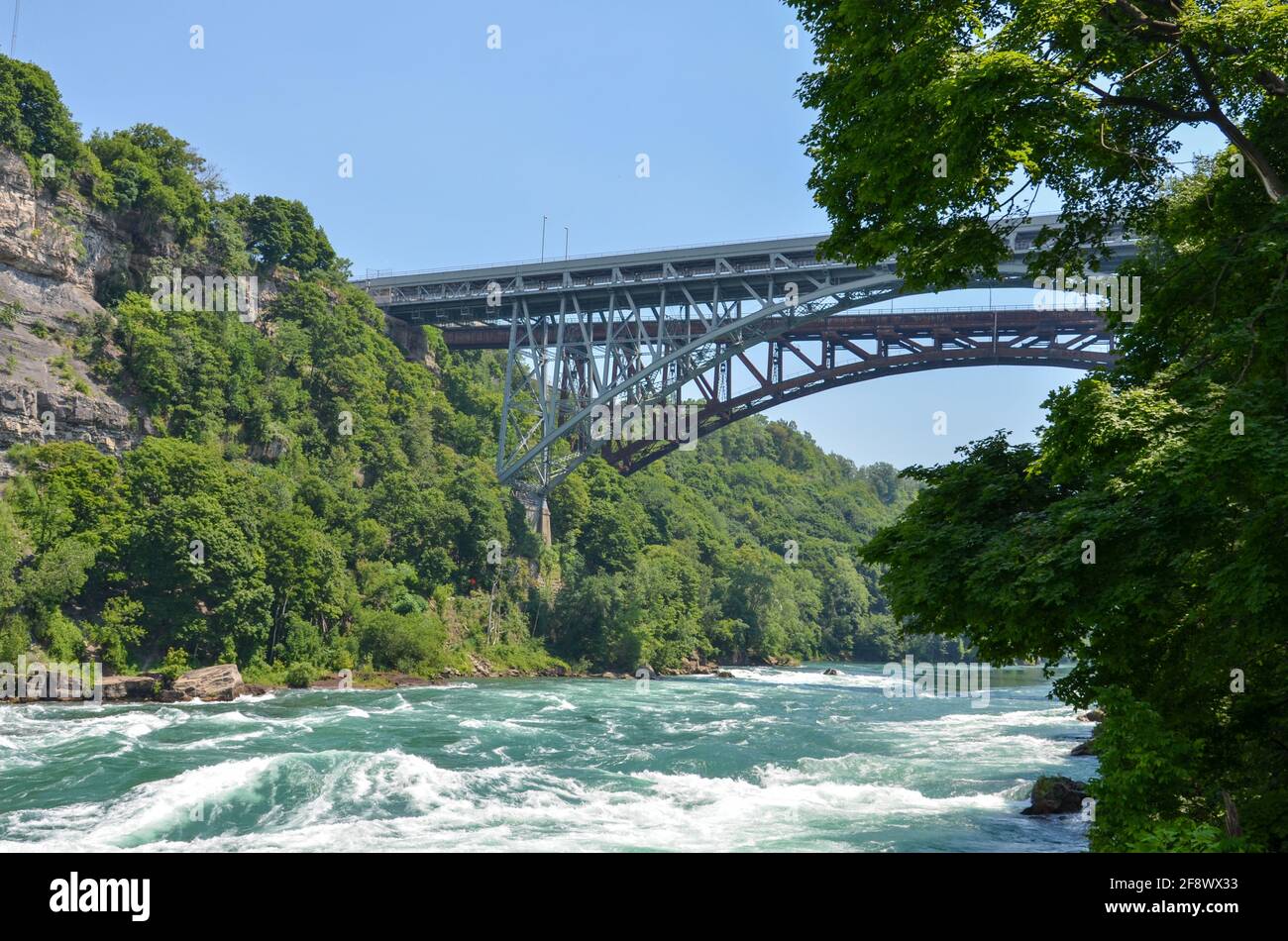 Bubbling rapids of the Niagara River flow over stones and rocks with ...