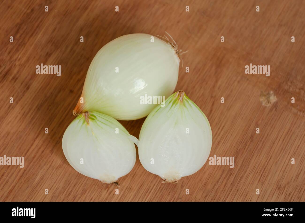 Whole And Cut Onions On Board Surface Stock Photo - Alamy