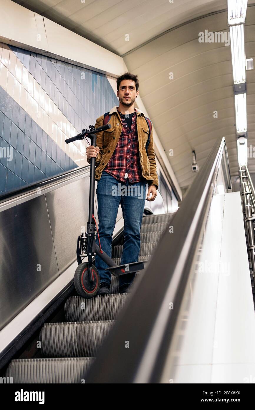 Man in stylish outfit with electric scooter in the mechanic stair of ...