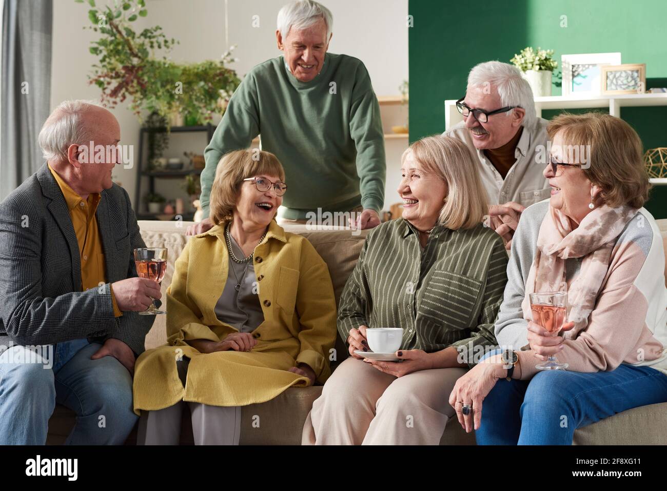 Happy old friends sitting on sofa and talking to each other during ...