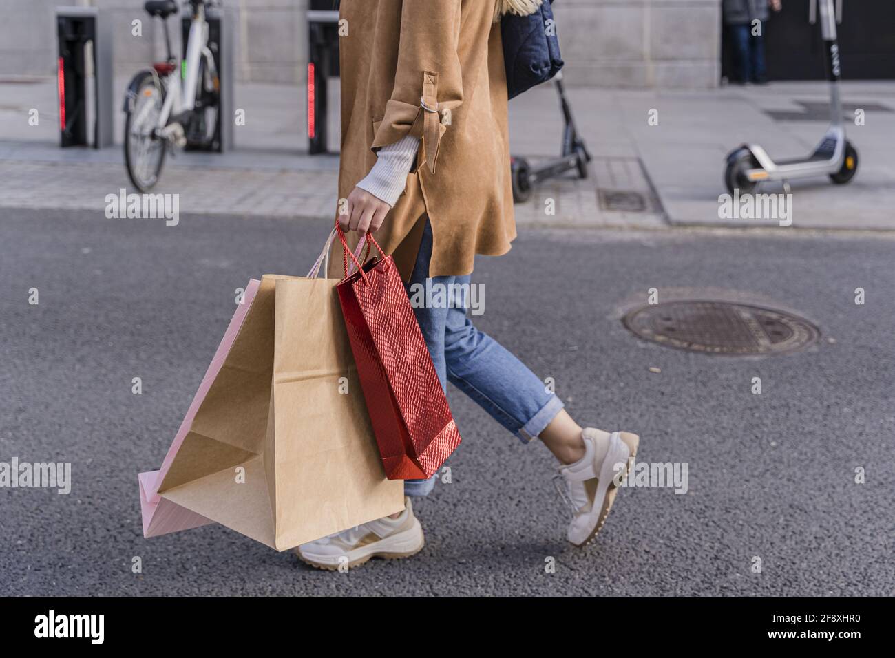Shallow focus of a woman holding shopping bags and walking down the ...