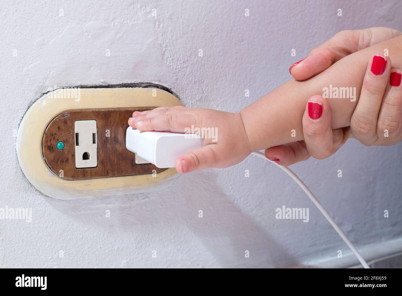 The boy puts his fingers in the electrical socket. Dangerous situation ...