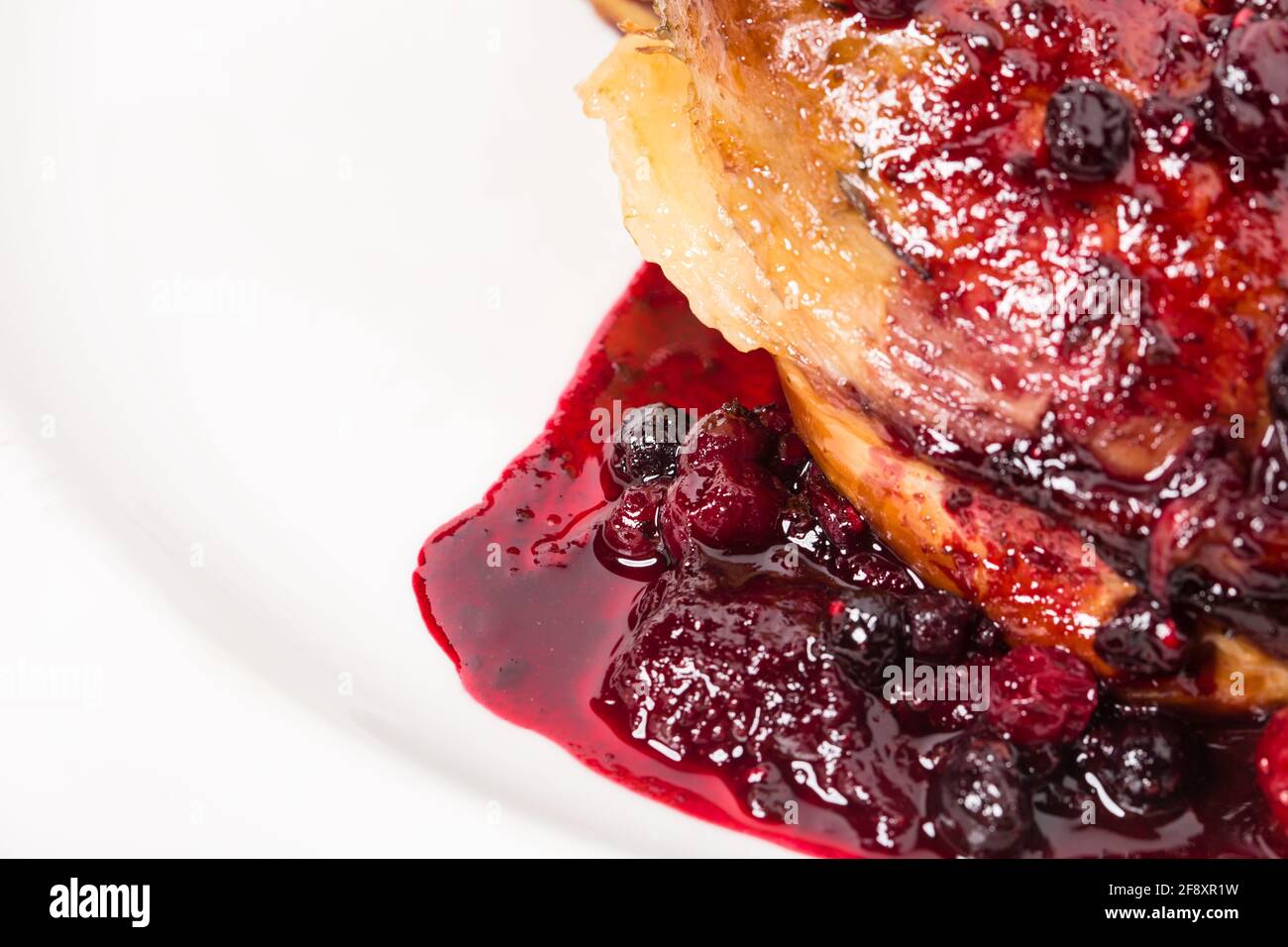 Delicious duck leg confit with red sauce and stewed berries. Macro ...