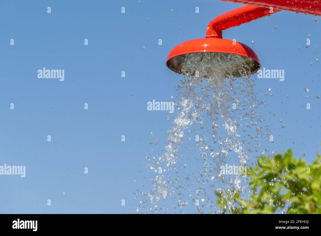 Water falling from bright colored red fountain to pool below. Copy ...