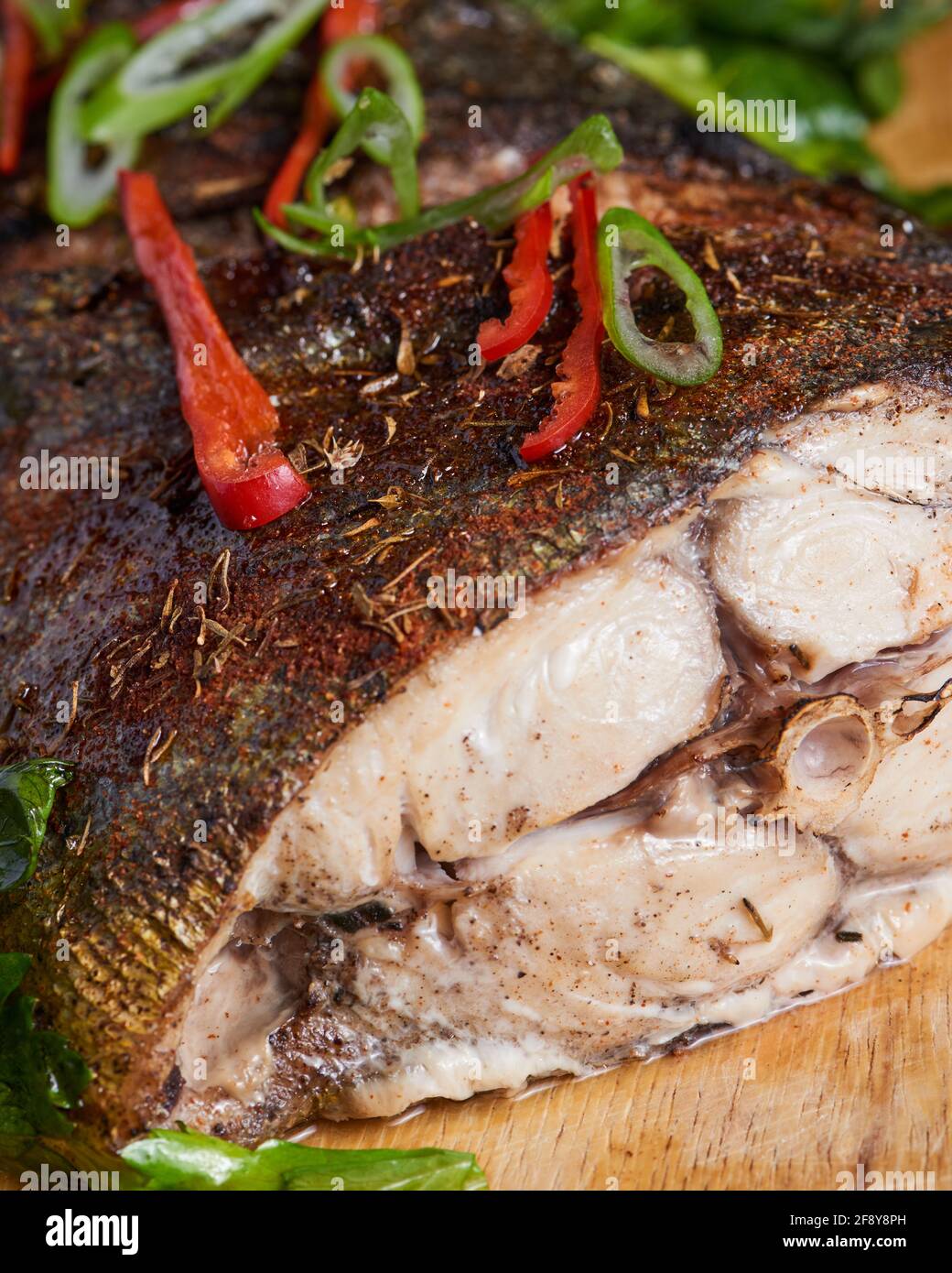 Vertical shot of delicious seasoned fish on a wooden plate Stock Photo ...