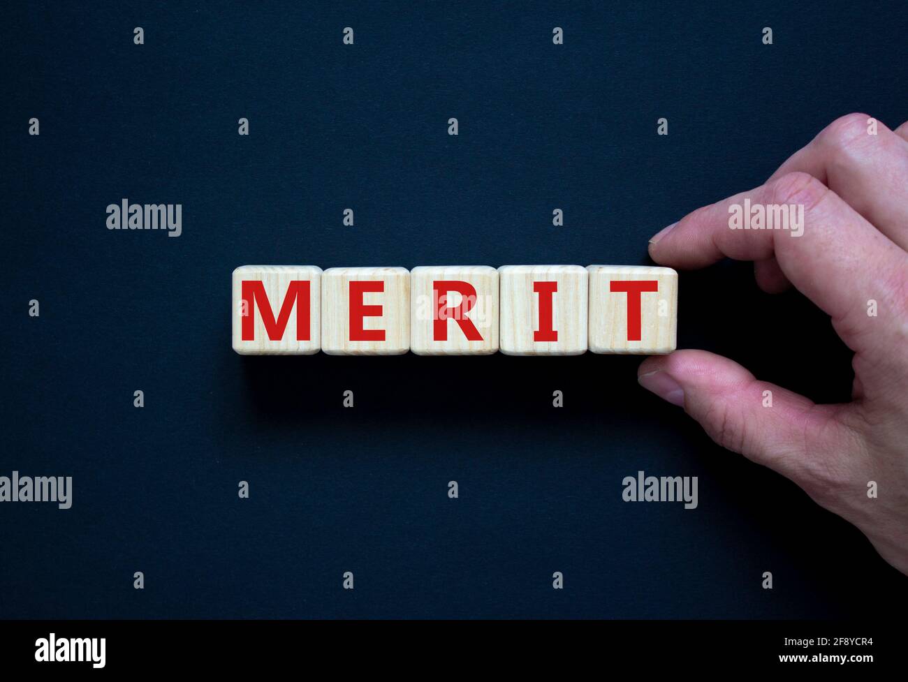 Merit symbol. Wooden cubes with the word 'merit'. Businessman hand ...