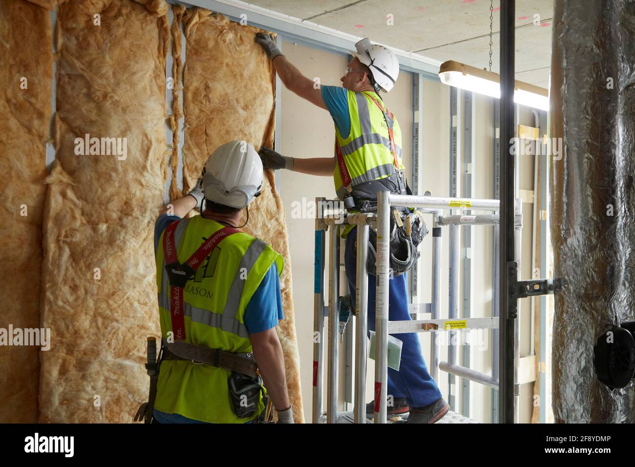 Construction workers on building site fit insulation to stud wall Stock ...