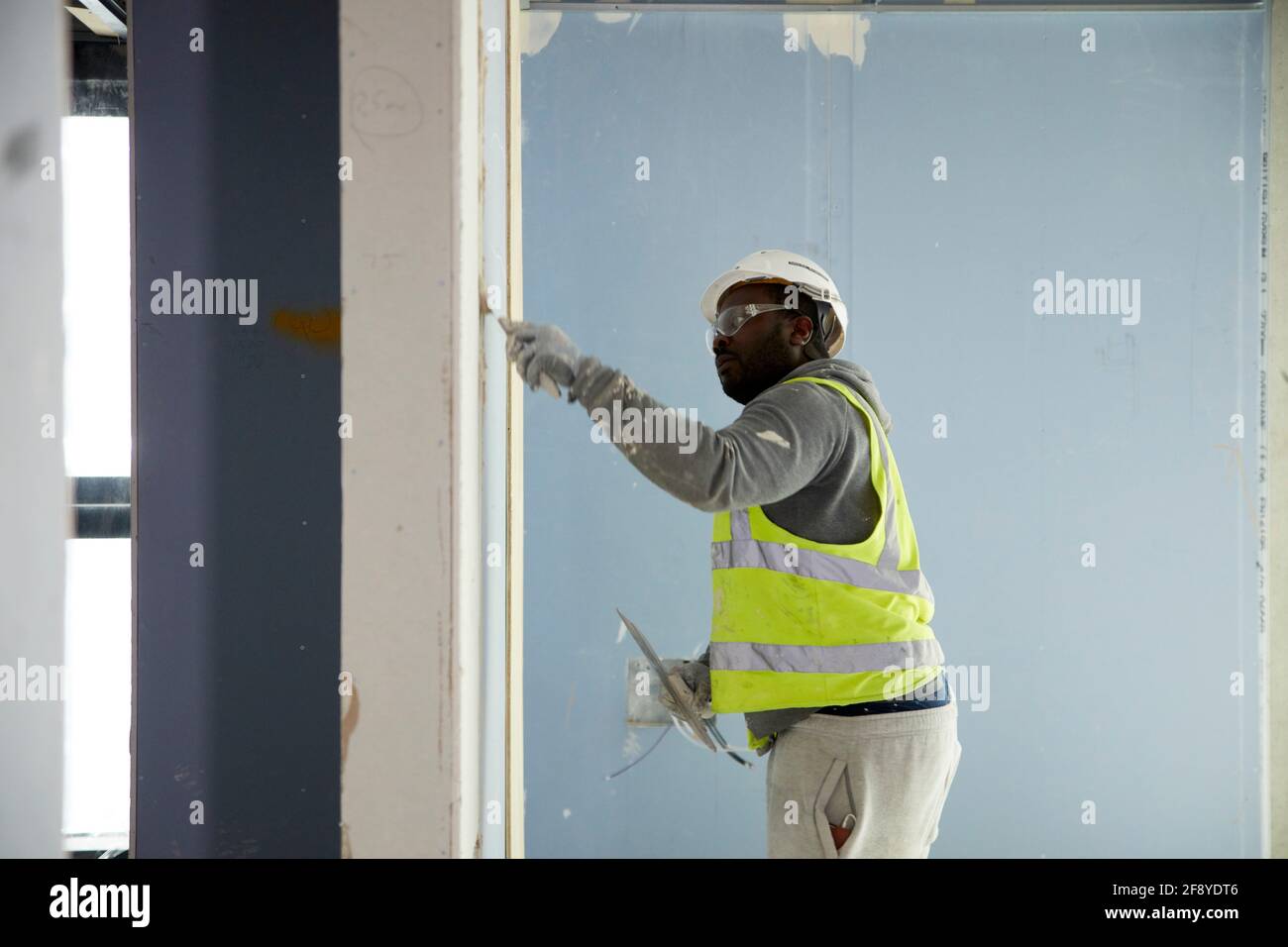 Construction worker on building site filled gap between dry lining with ...