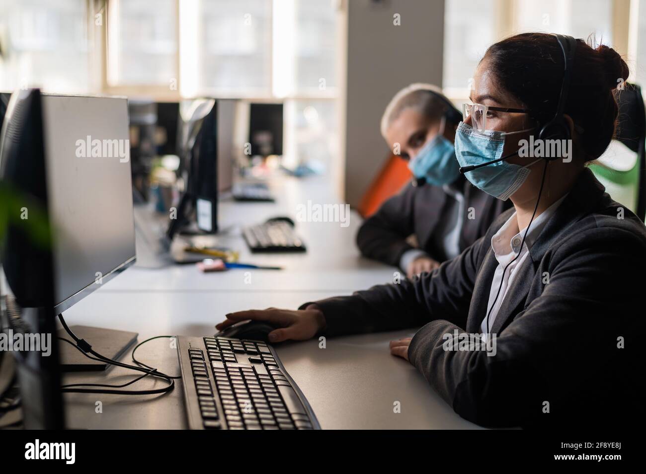 Two women in medical masks are working in the office. Female call ...