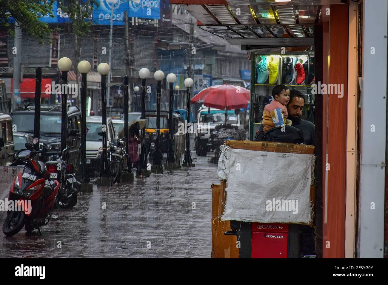 A man with his son as they take a shelter at a shop during the rainfall ...