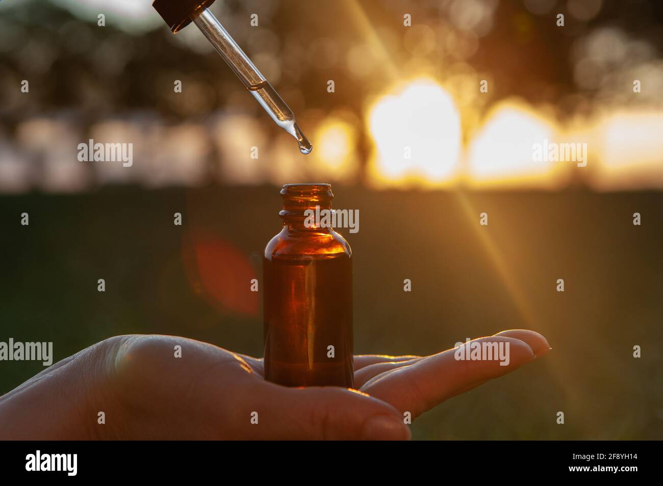 Women holding a dropper bottle of herbal essential oil on the blurred ...