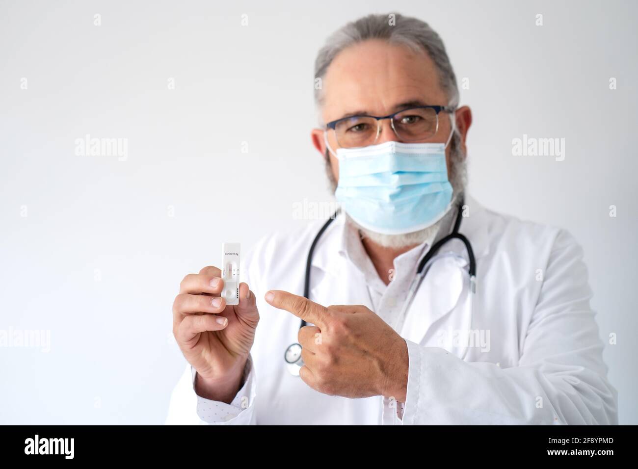 Portrait of senior doctor in surgical mask showing Covid-19 PCR result ...