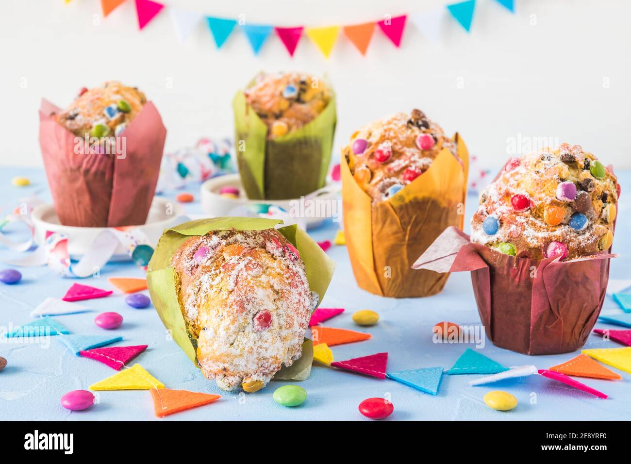 Colourful muffins on blue, decorated with a party garland and chocolate ...