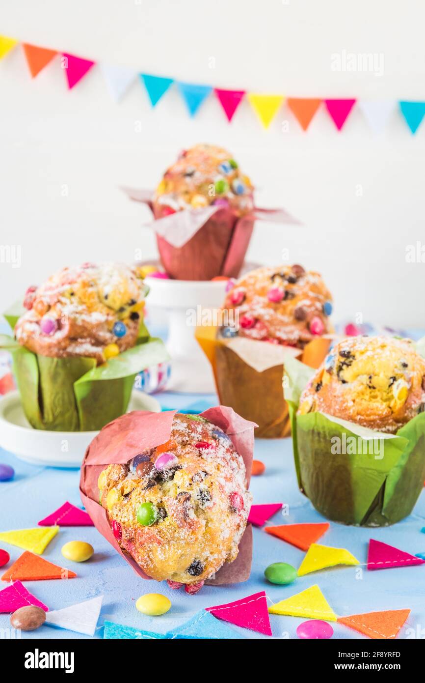 Colourful muffins on blue, decorated with a party garland and chocolate ...