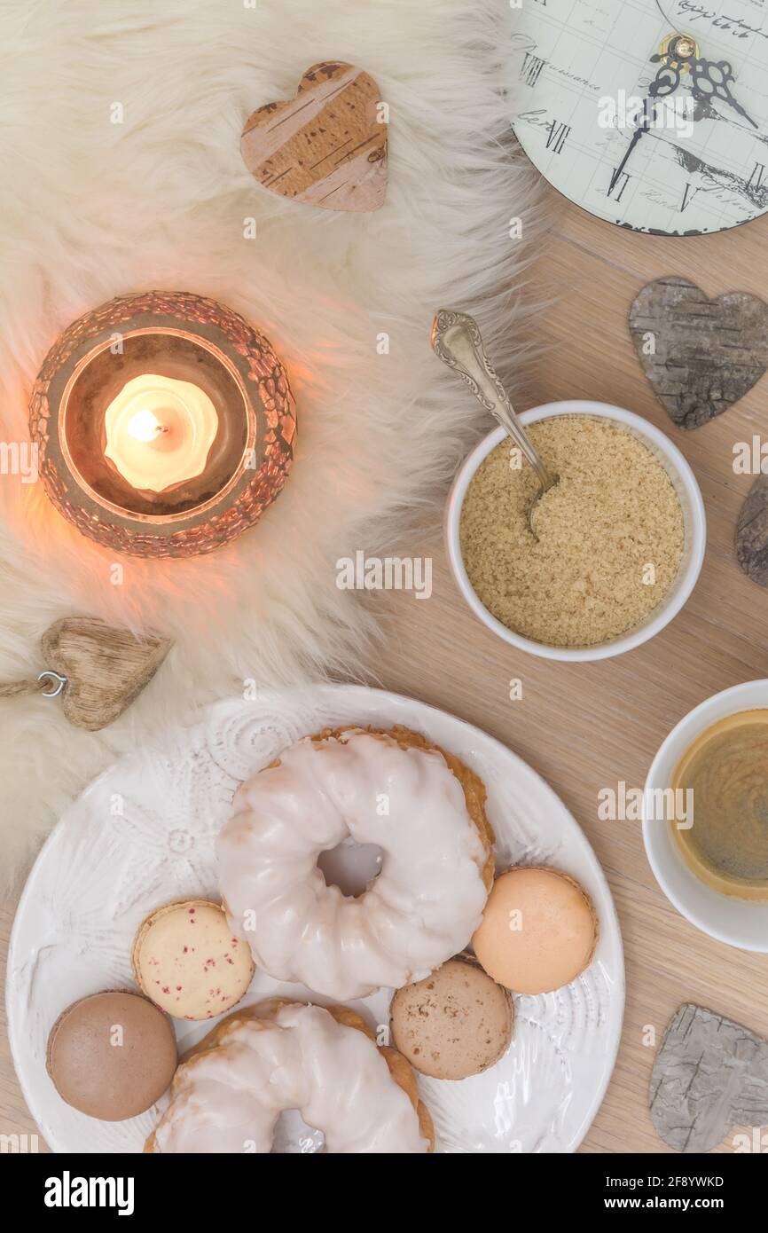 Scene of a cozy coffee break with macarons, donuts, and candle light on ...