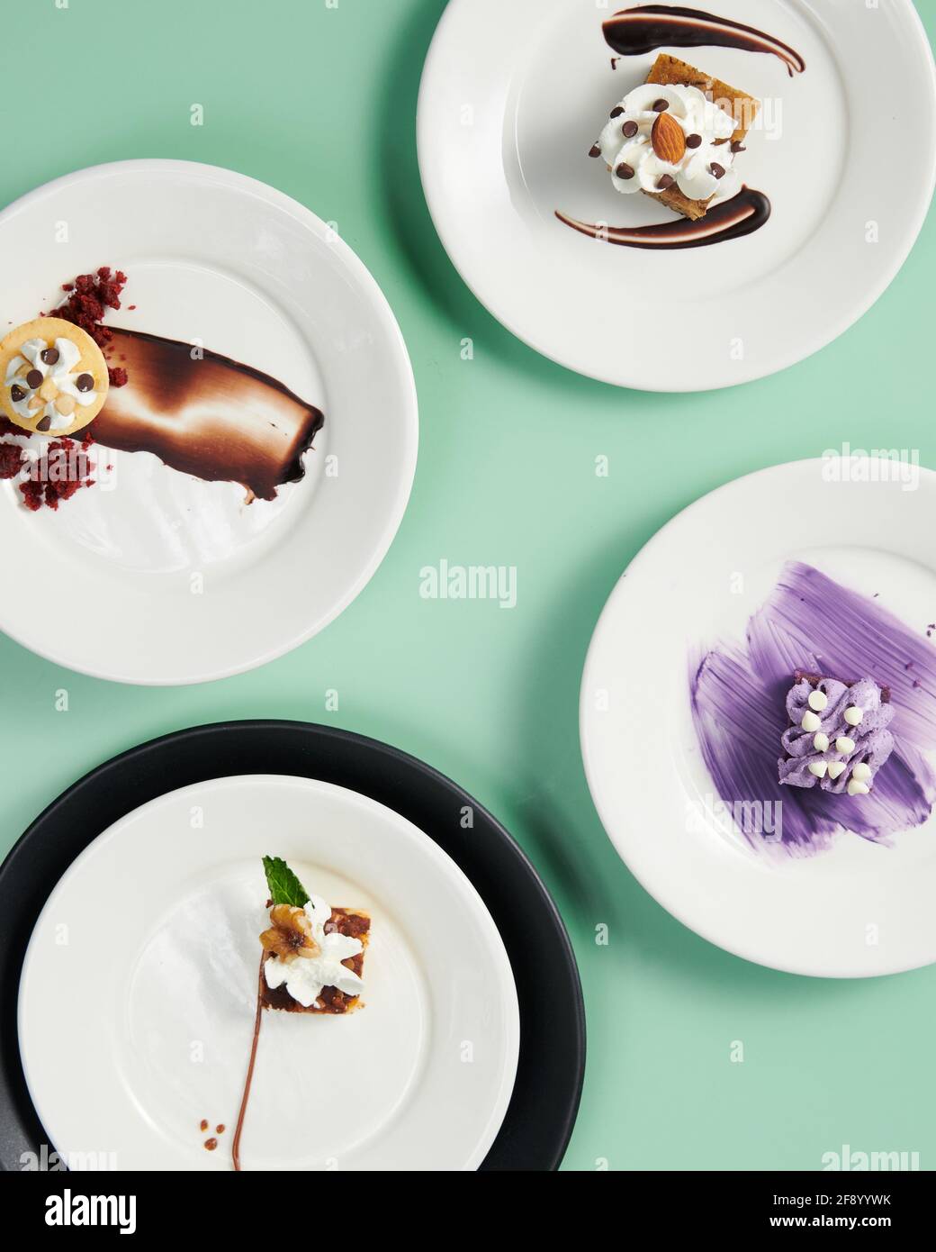 Vertical top view of small cakes served on decorated plates on a minty ...