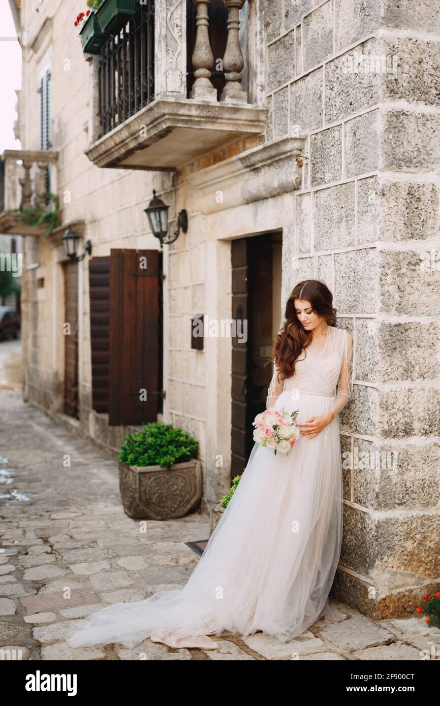 A bride with a wedding bouquet stands at a beautiful ancient building ...