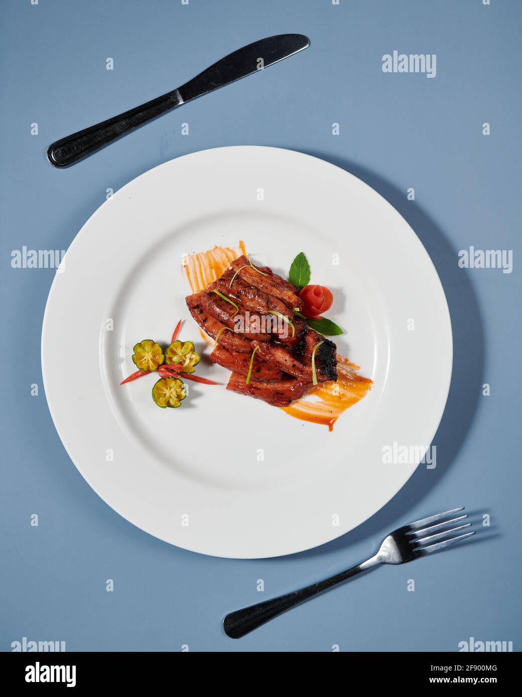 Vertical top view of decorated cooked meat with sauce served on a white ...