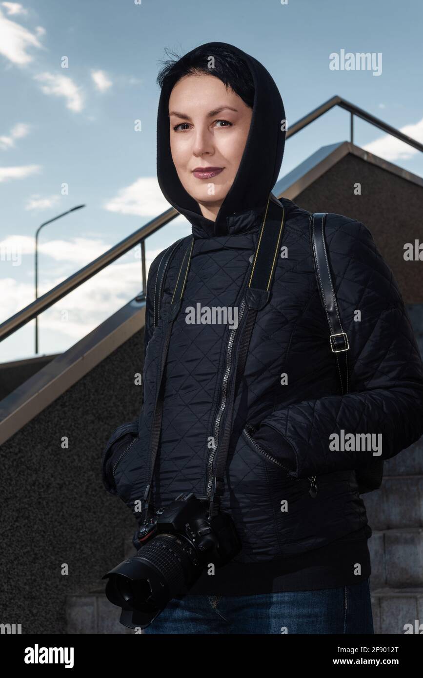 Smiling middle-aged female photographer with professional dslr camera ...