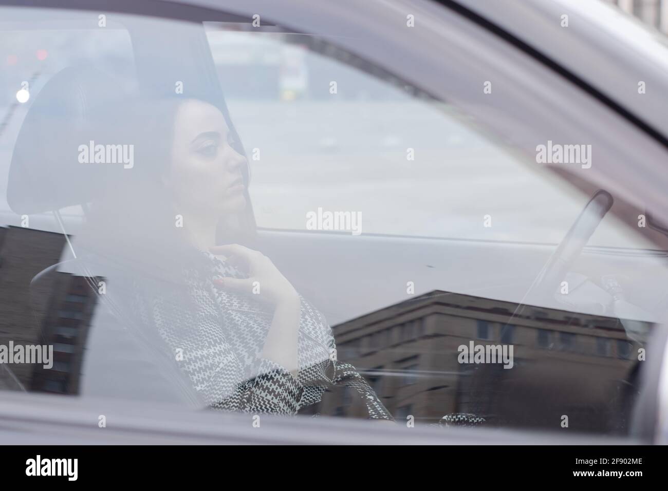 portrait of an attractive brunette in grey checkered dress in a black ...