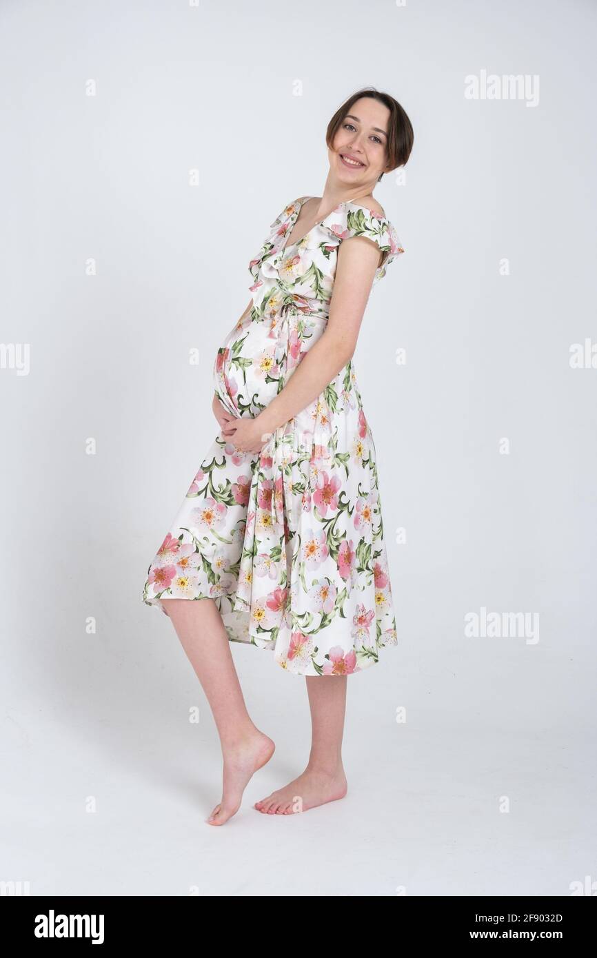 Studio portrait of cheerful young pregnant woman in summer dress on ...