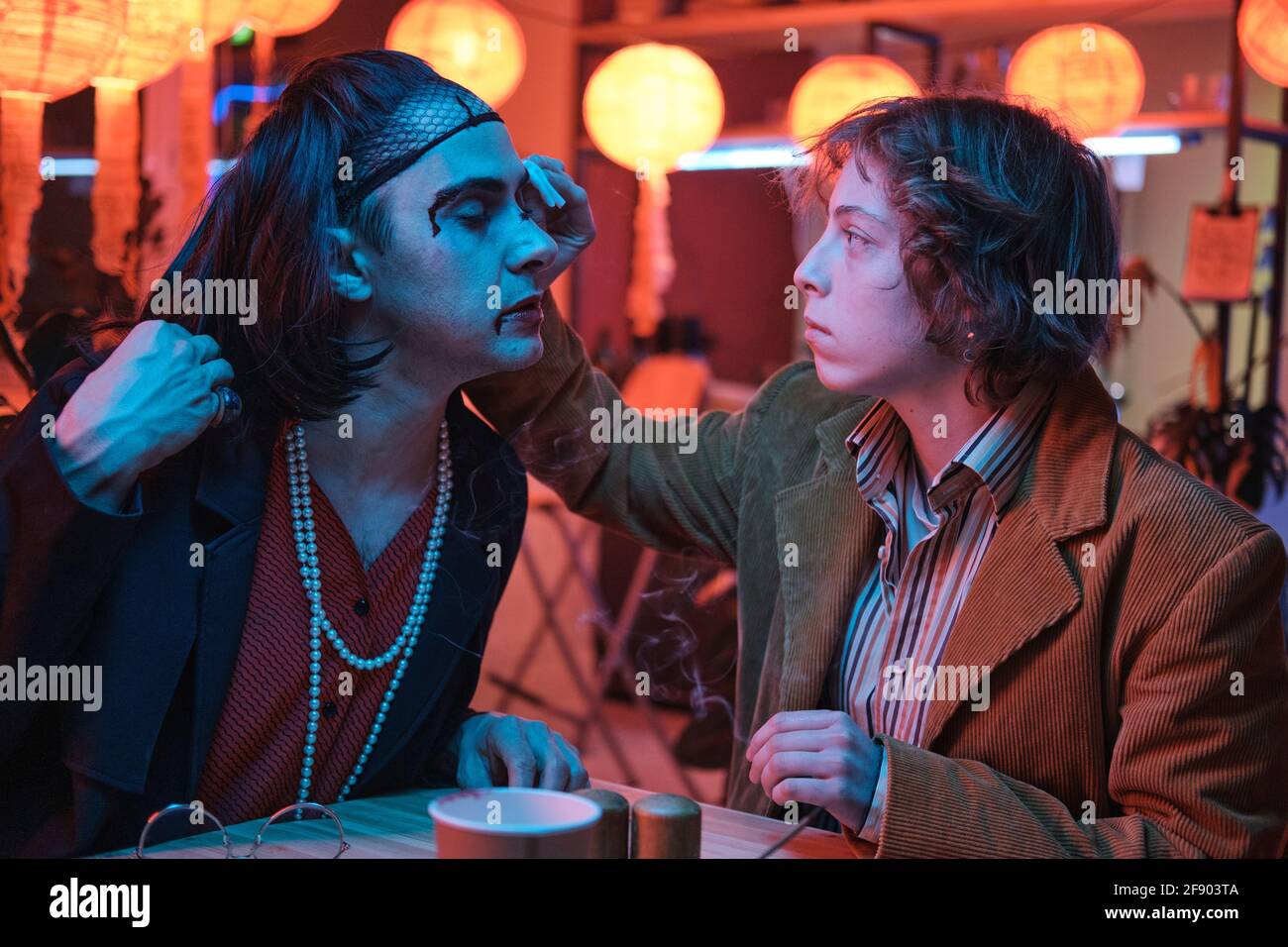 Young woman treating the wounds on the face of her transgender friend ...