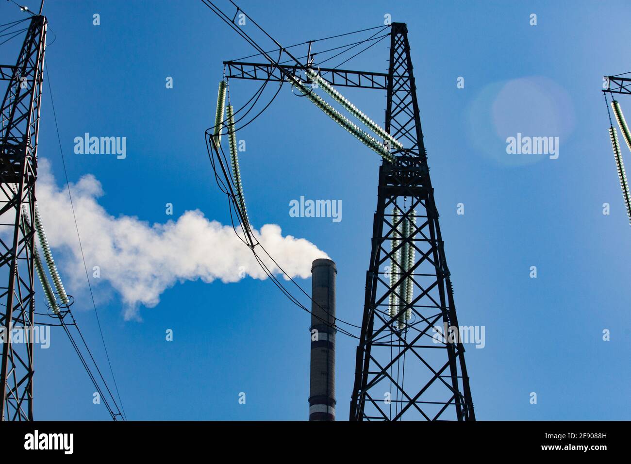 Electric pole with insulators on blue sky and smocking plant chimney ...
