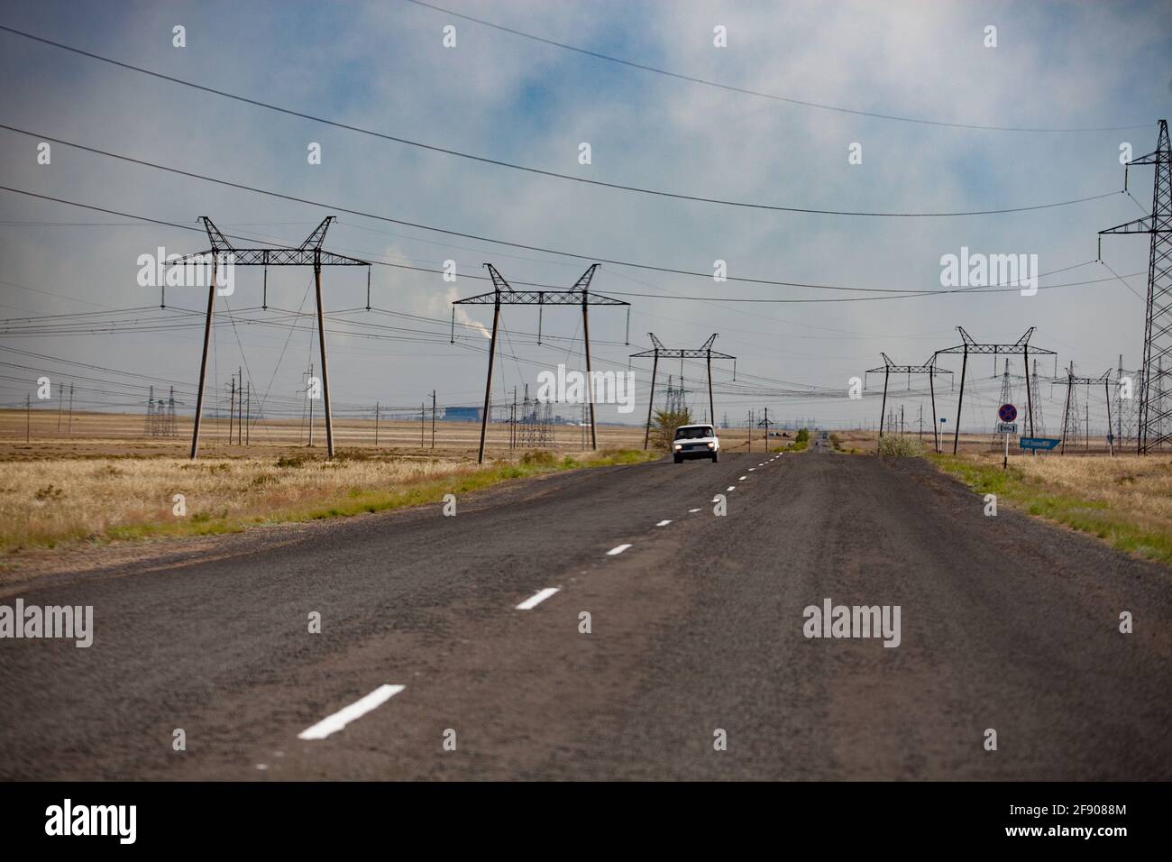 Electric pylons (poles) and cables on blue sky background. Asphalt road ...