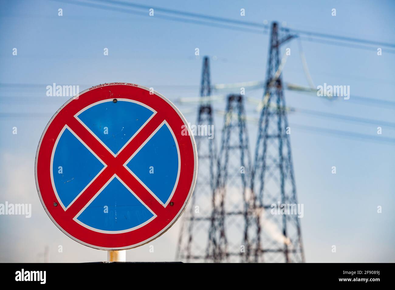Road sign "Stopping and parking prohibited". On blurred electric mast ...