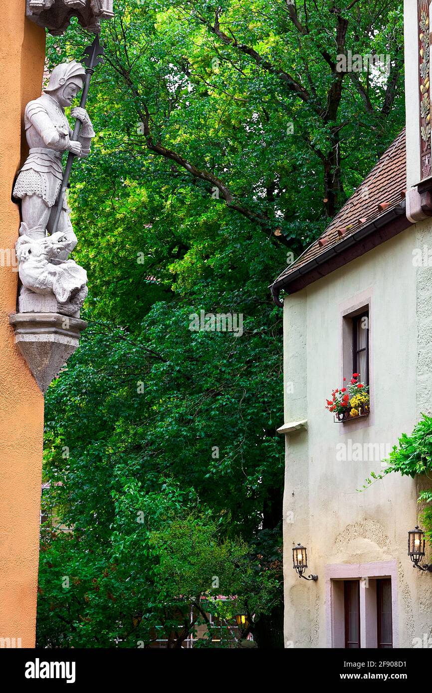Sculpture of knight on building corner above street with flowers in ...