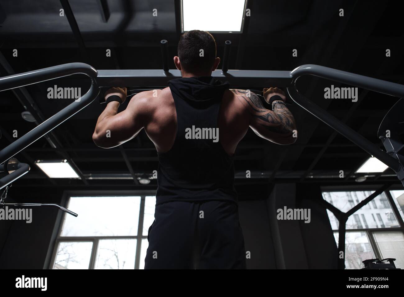 Low angle shot of a muscular male bodybuilder doing pull ups at the gym ...