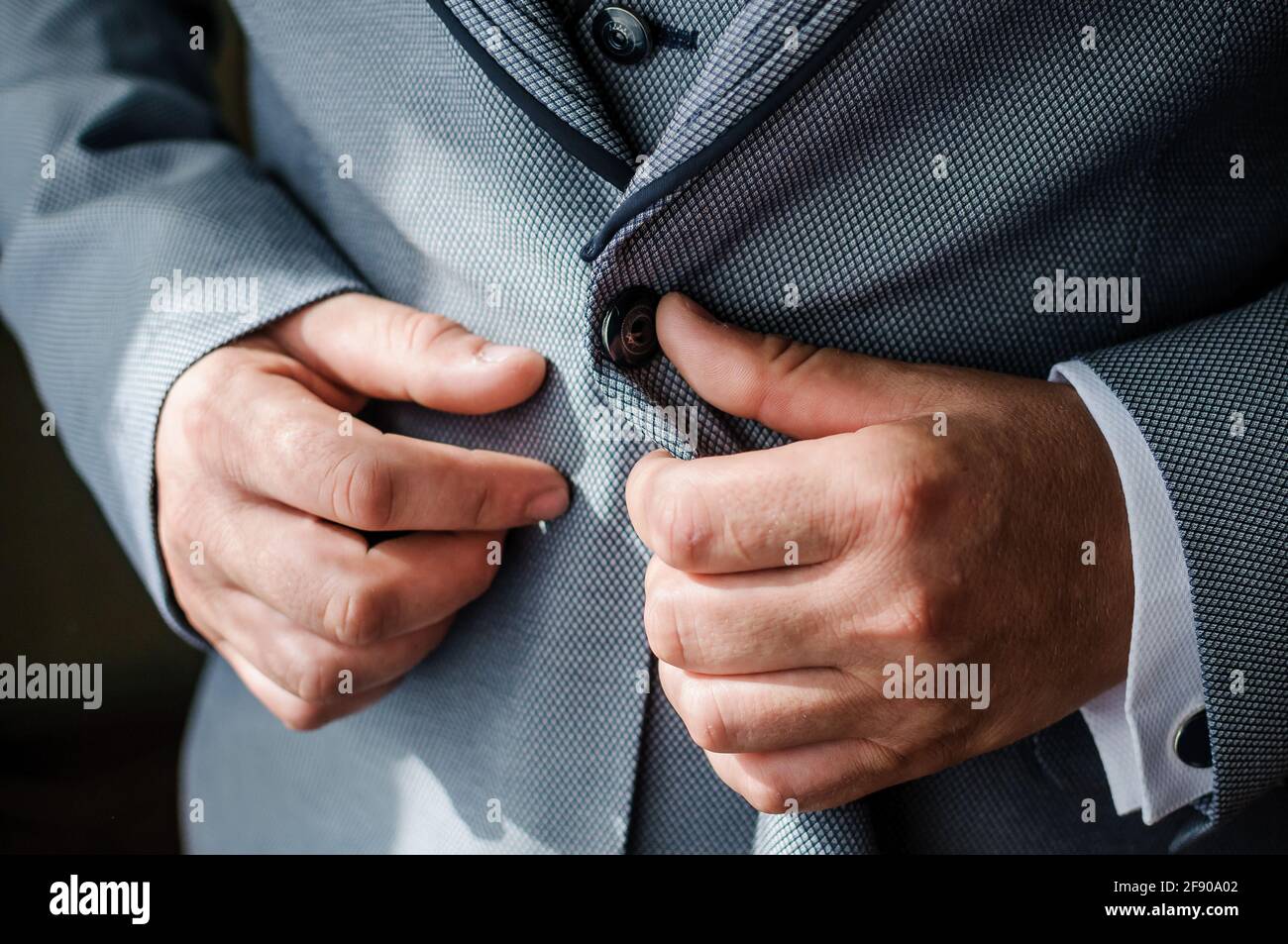 The man fasten a button on his jacket. The groom fasten a button on his ...