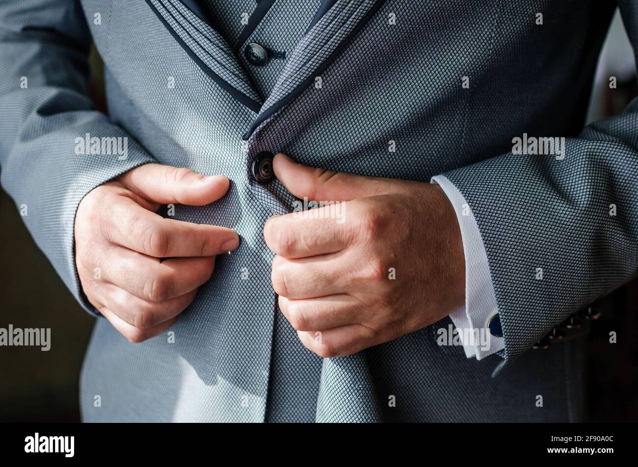 The man fasten a button on his jacket. The groom fasten a button on his ...