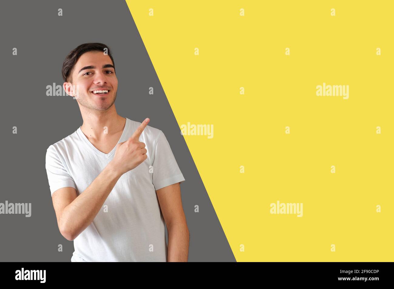 Man pointing away with finger standing against gray yellow background ...