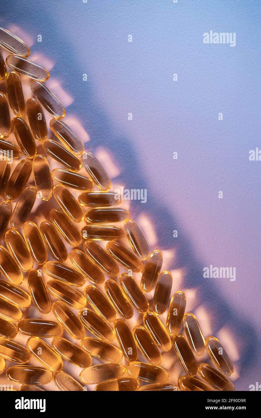 handful of golden fish oil capsules omega 3 vitamins on purple ...