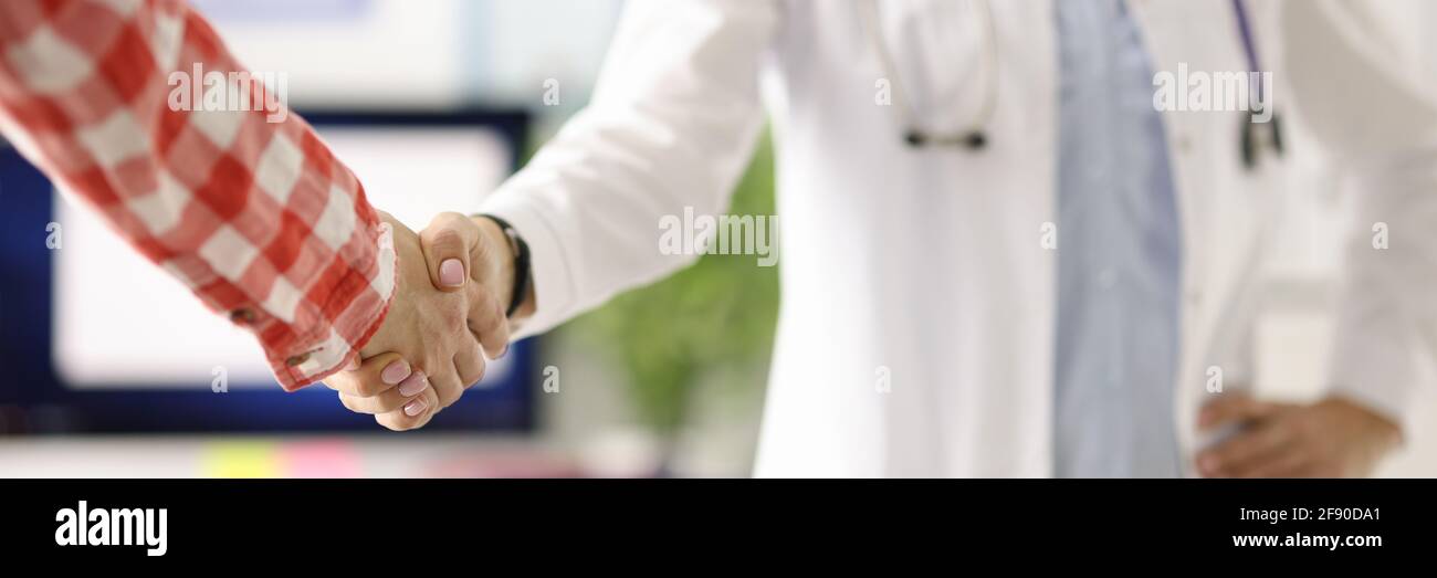 Doctor with stethoscope around neck shaking patients hand in clinic ...