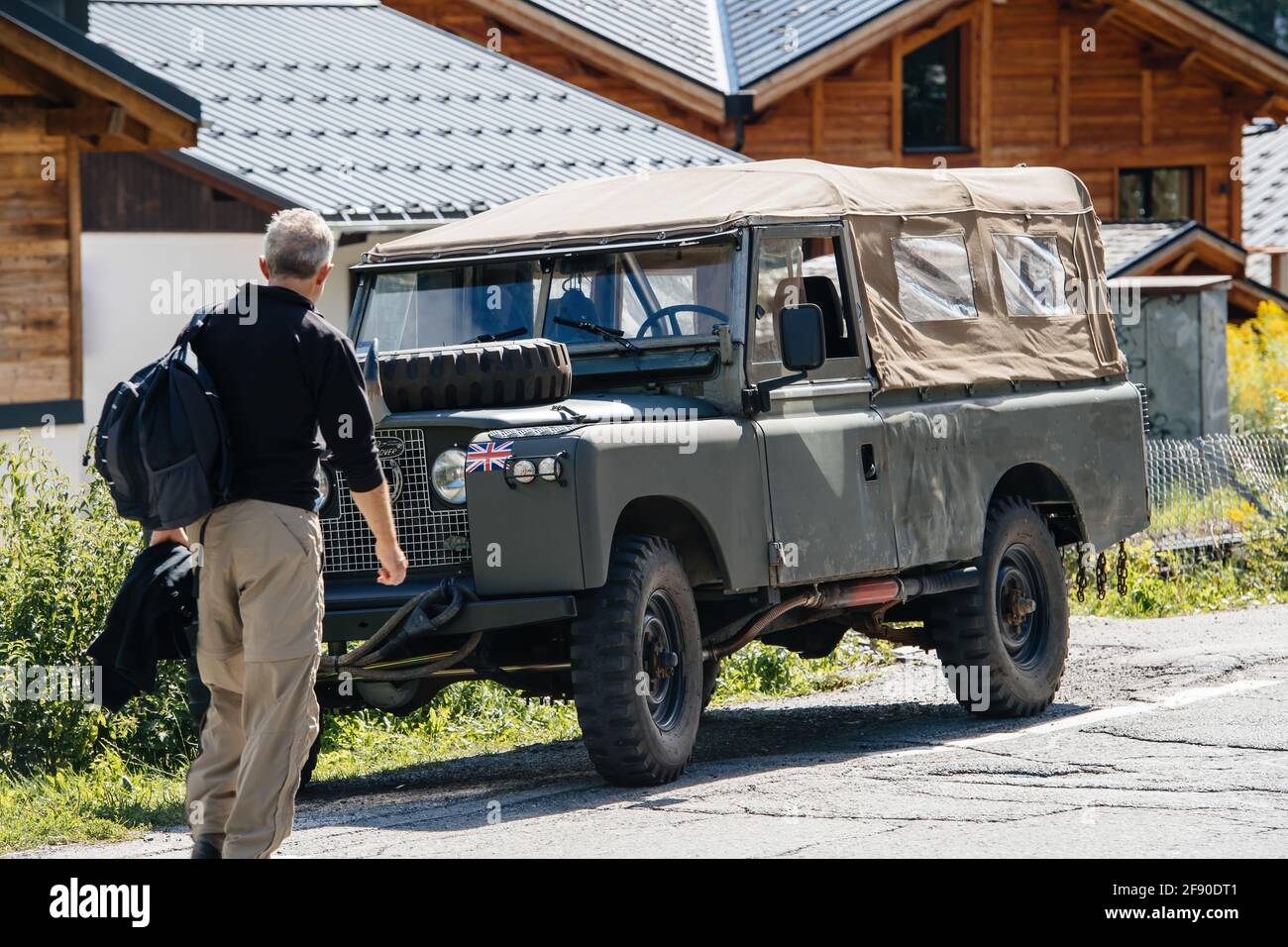 Rear view of adventure tourist man walking toward to Land Rover ...