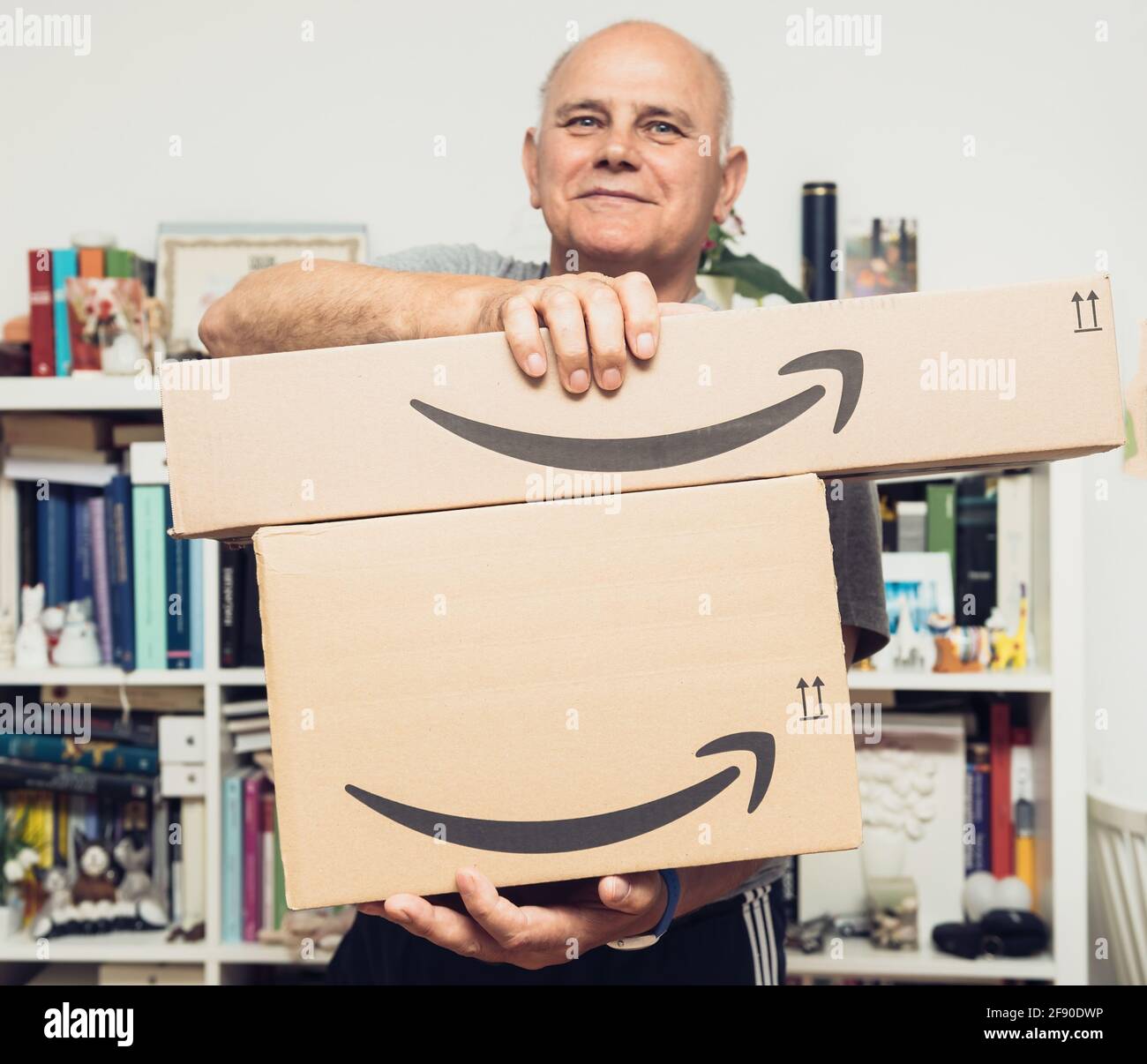 Senior man smiling while holding two new Amazon Prime parcel logotype ...