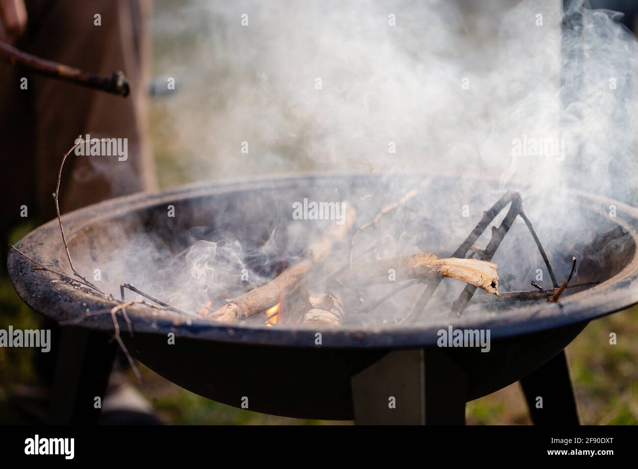 Fireplace with branches of a tree and white smoke, iron barbecue grill ...