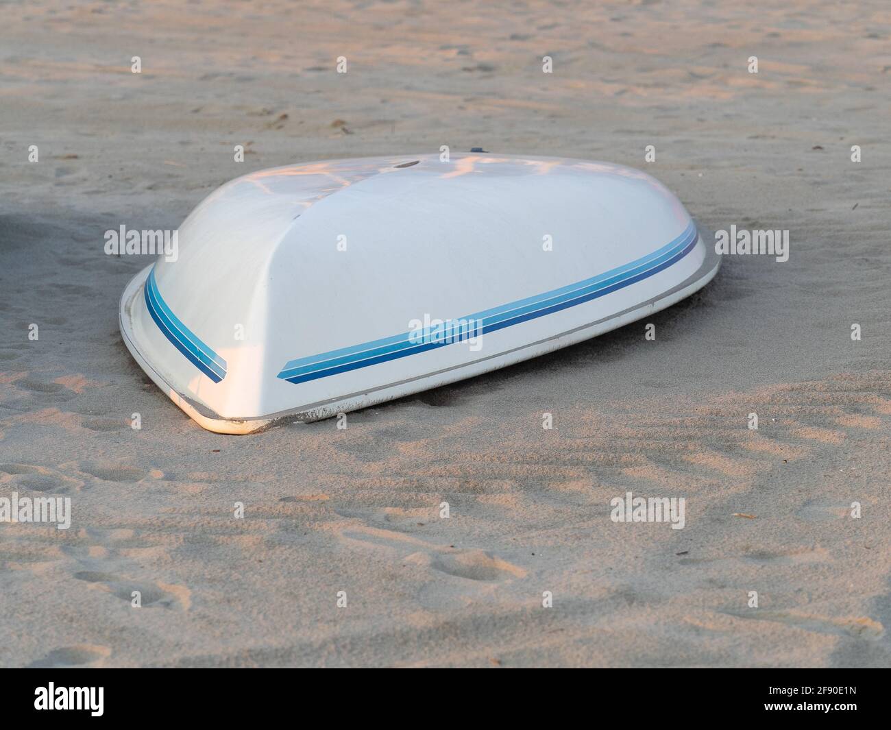 small white sailing boat capsized on the beach to protect from damages ...