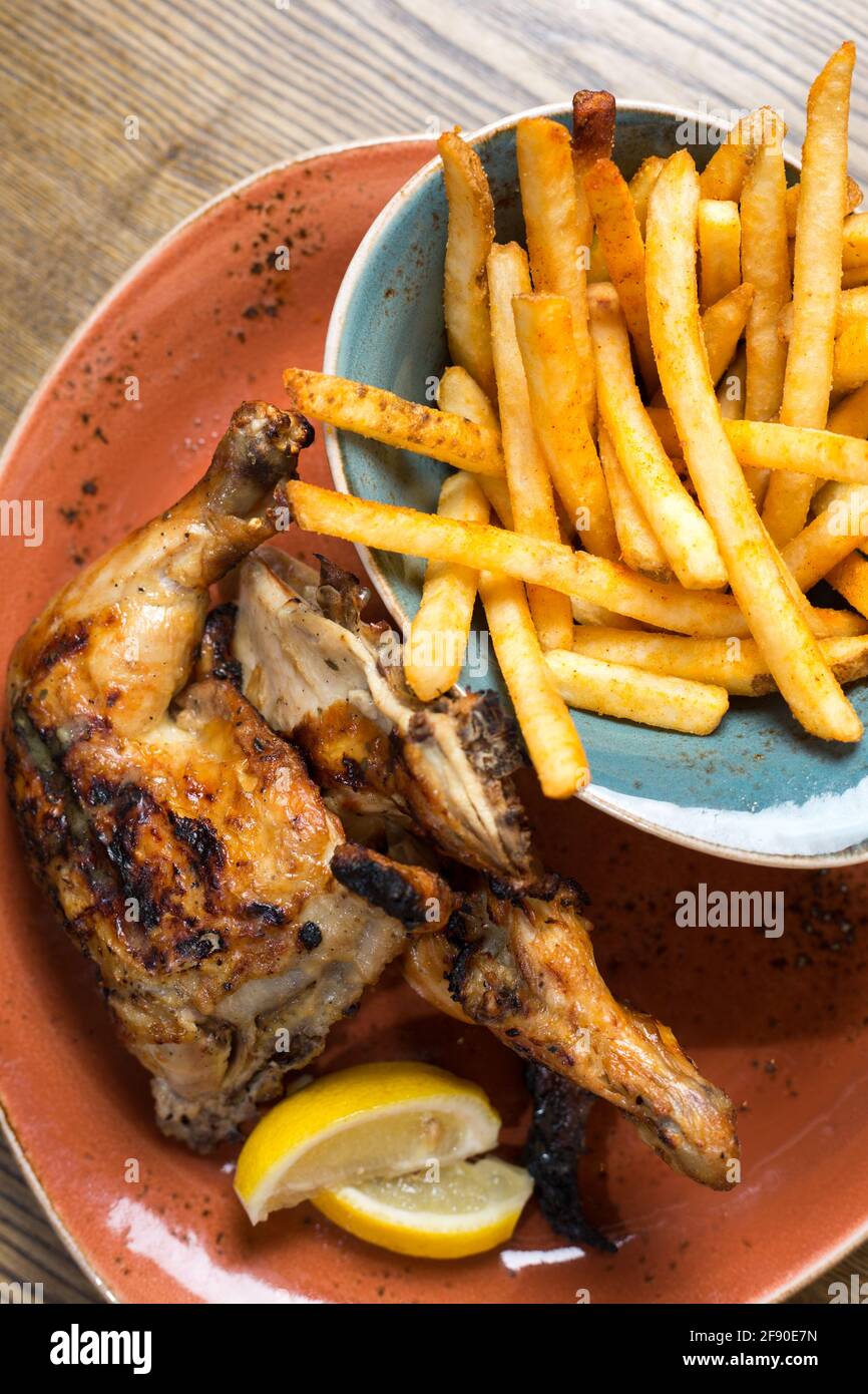 Vertical top view of a plate with grilled chicken and french fries ...