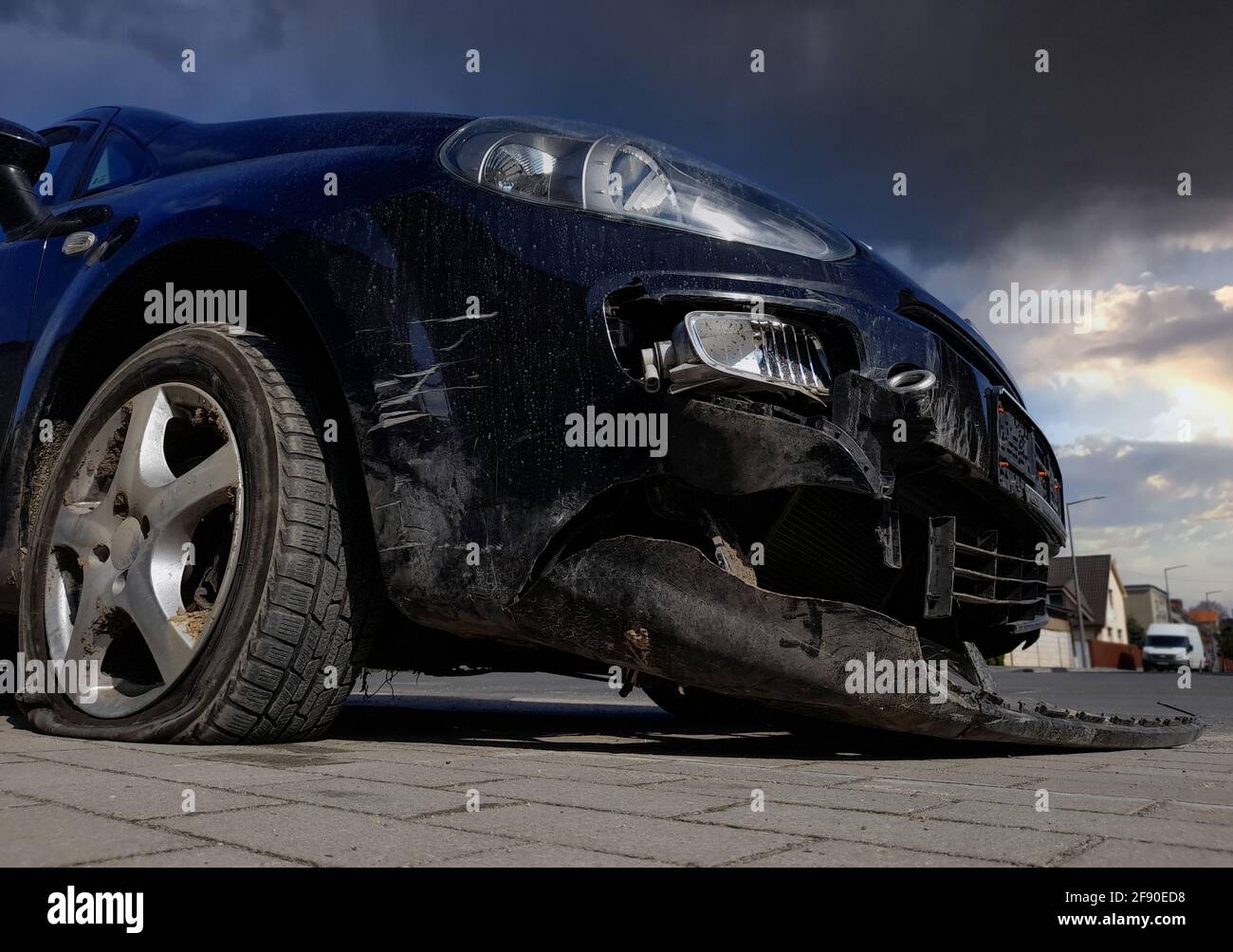Low angle shot of a damaged front bumper and torn tire of a car after ...