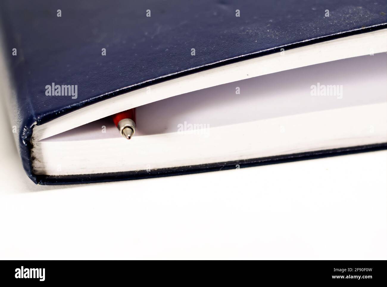 Red ballpoint pen on the blank white pages of a closed notebook ...