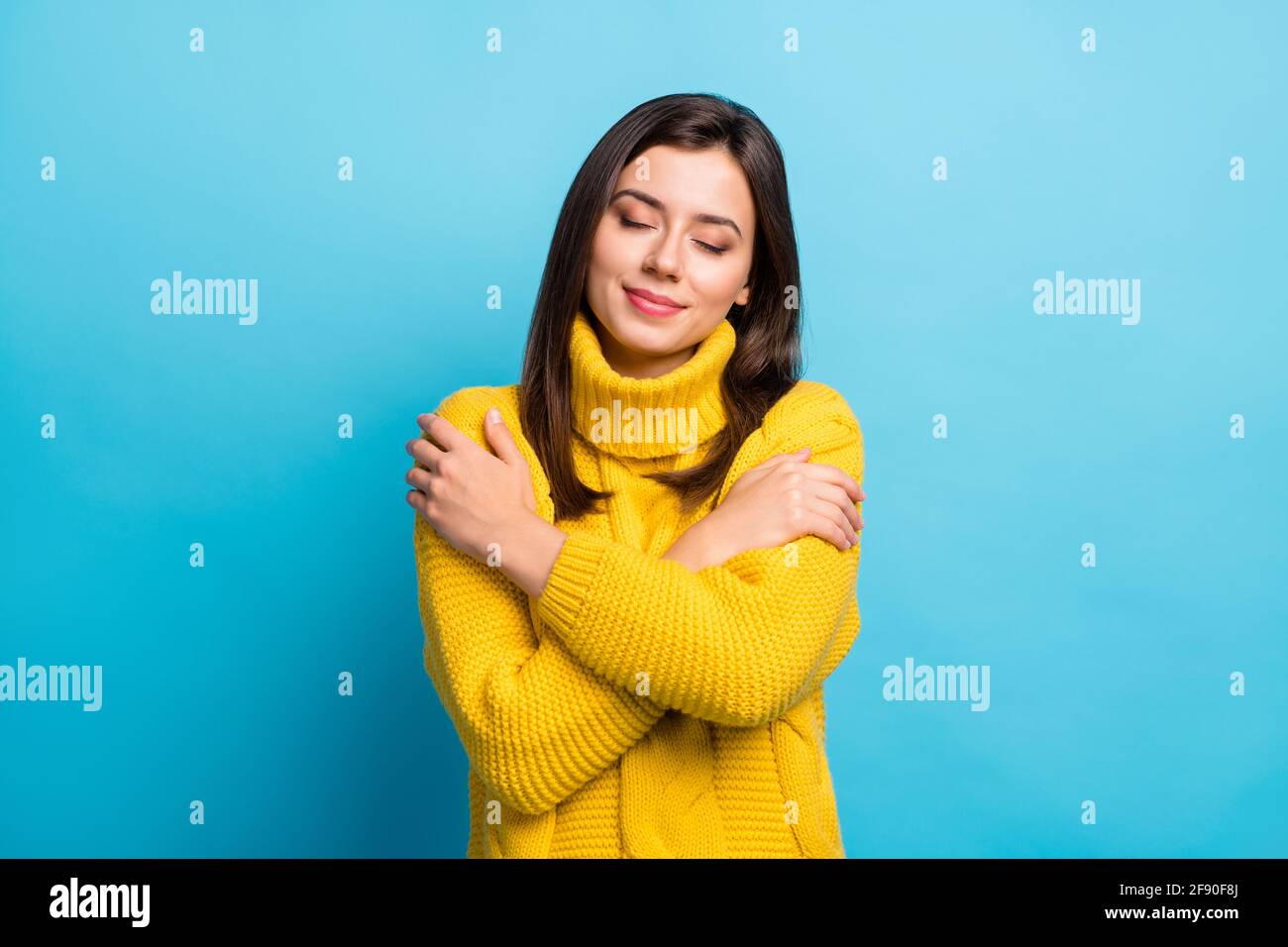 Close-up portrait of lovely cheery dreamy girl hugging herself enjoying ...