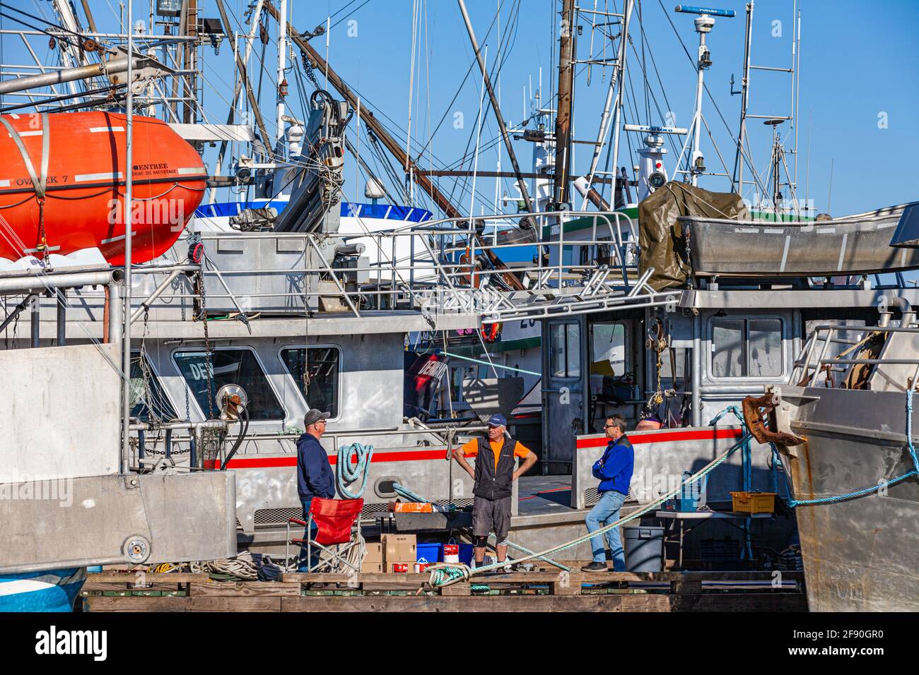Men on a floating dock taking a break from working on a fishing boat in ...