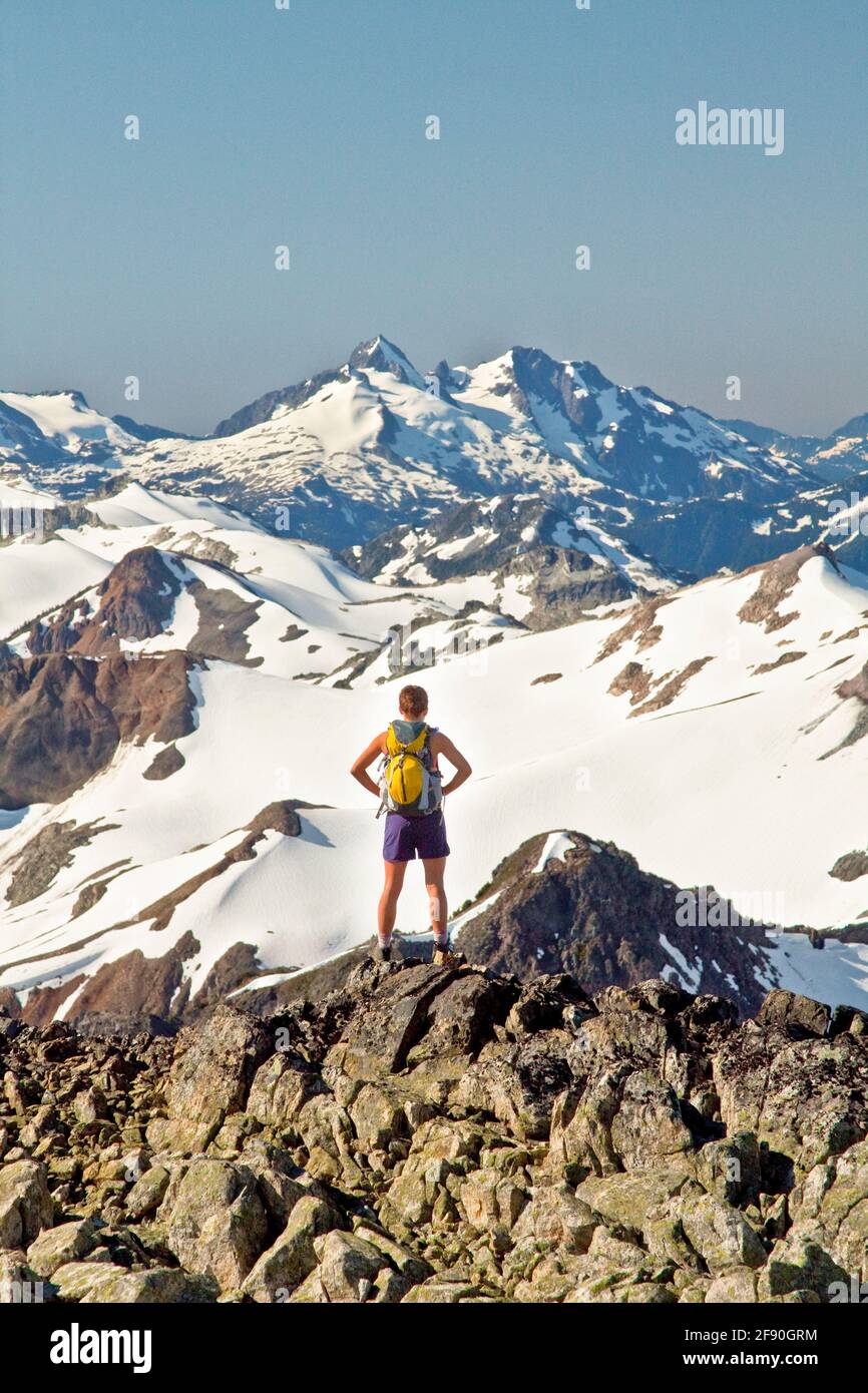 Rear view of attractive fit woman on mountain summit wearing backpack ...
