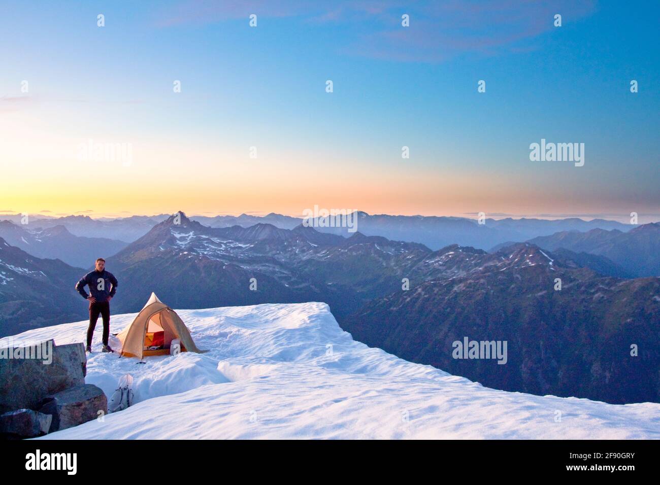 Climber standing next to tent on mountain summit, Whistler, Canada ...