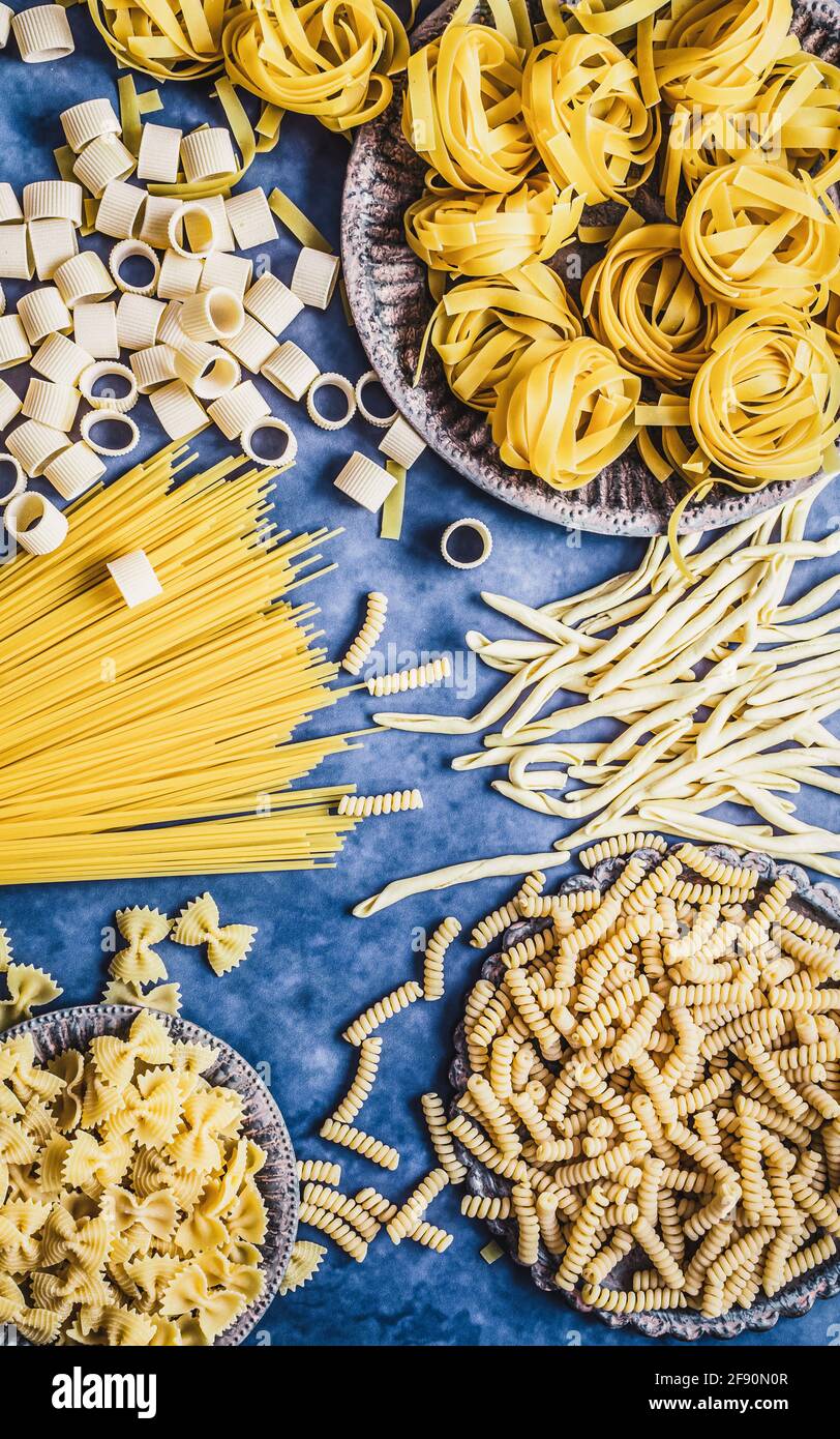 Dry pasta shapes on a blue background Stock Photo - Alamy