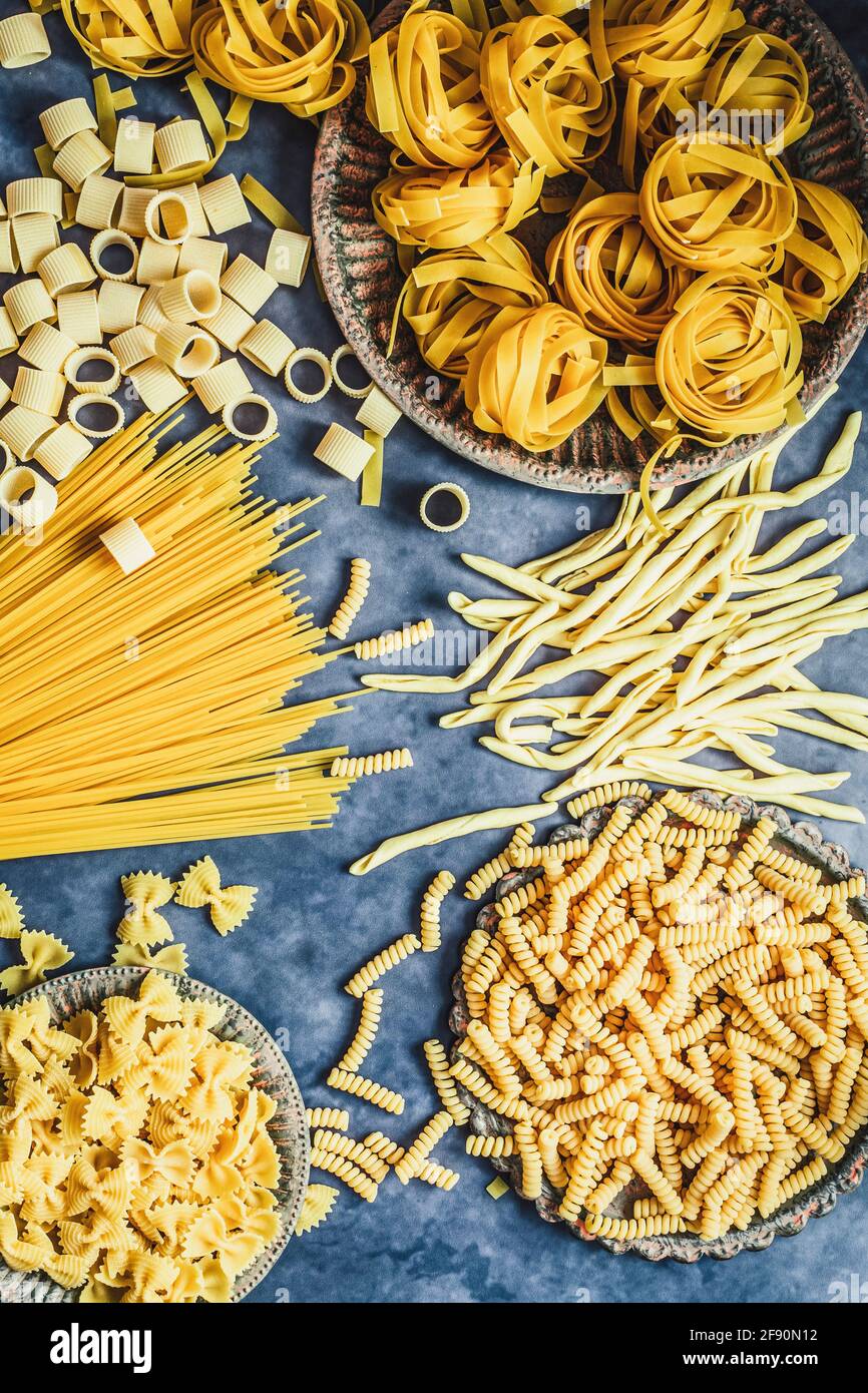 Dry pasta shapes on a blue background Stock Photo - Alamy