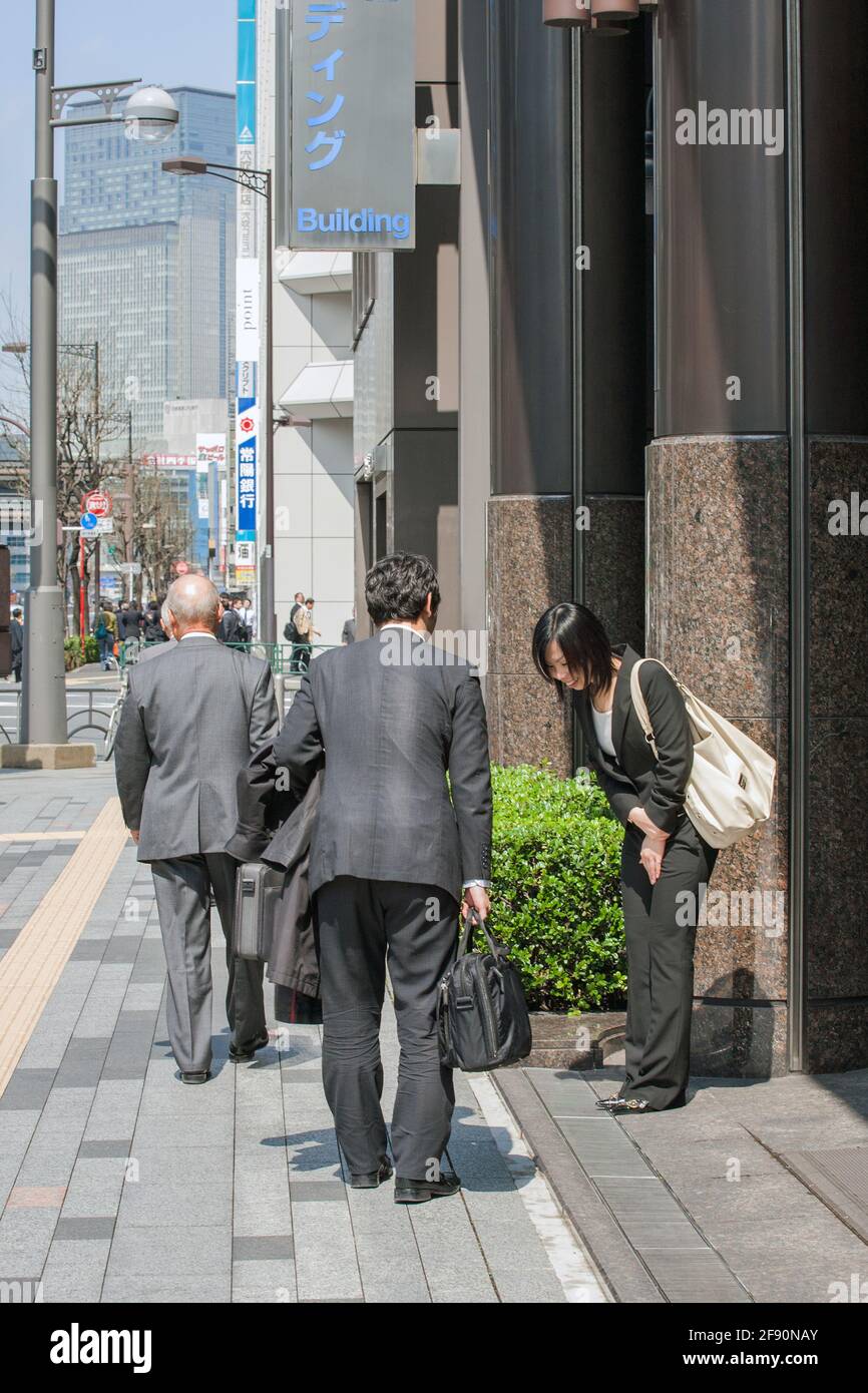 Japanese male and female office workers bowing (ojigi) with each other ...